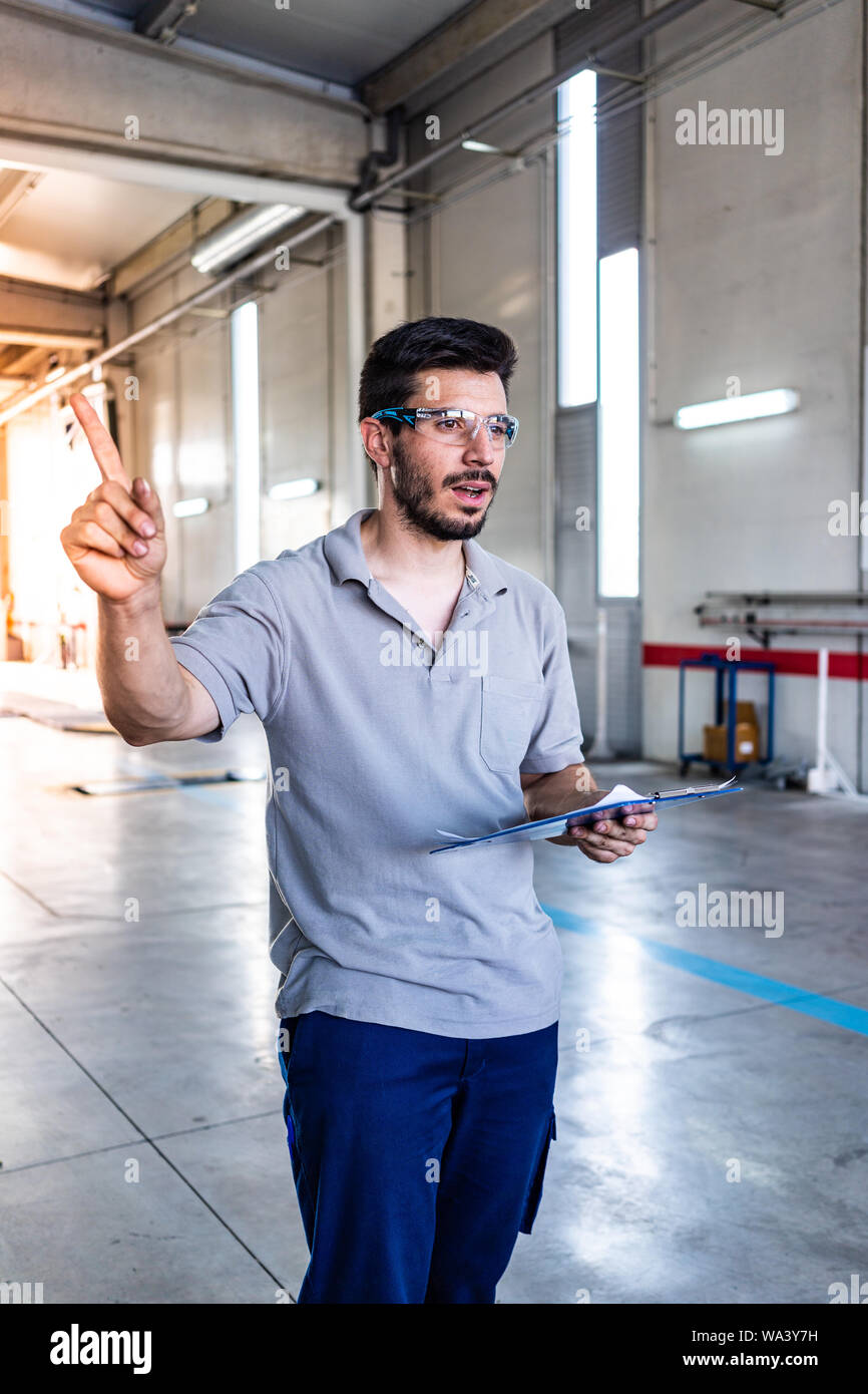 Technician with safety glasses checking the turn lights of a car during ...