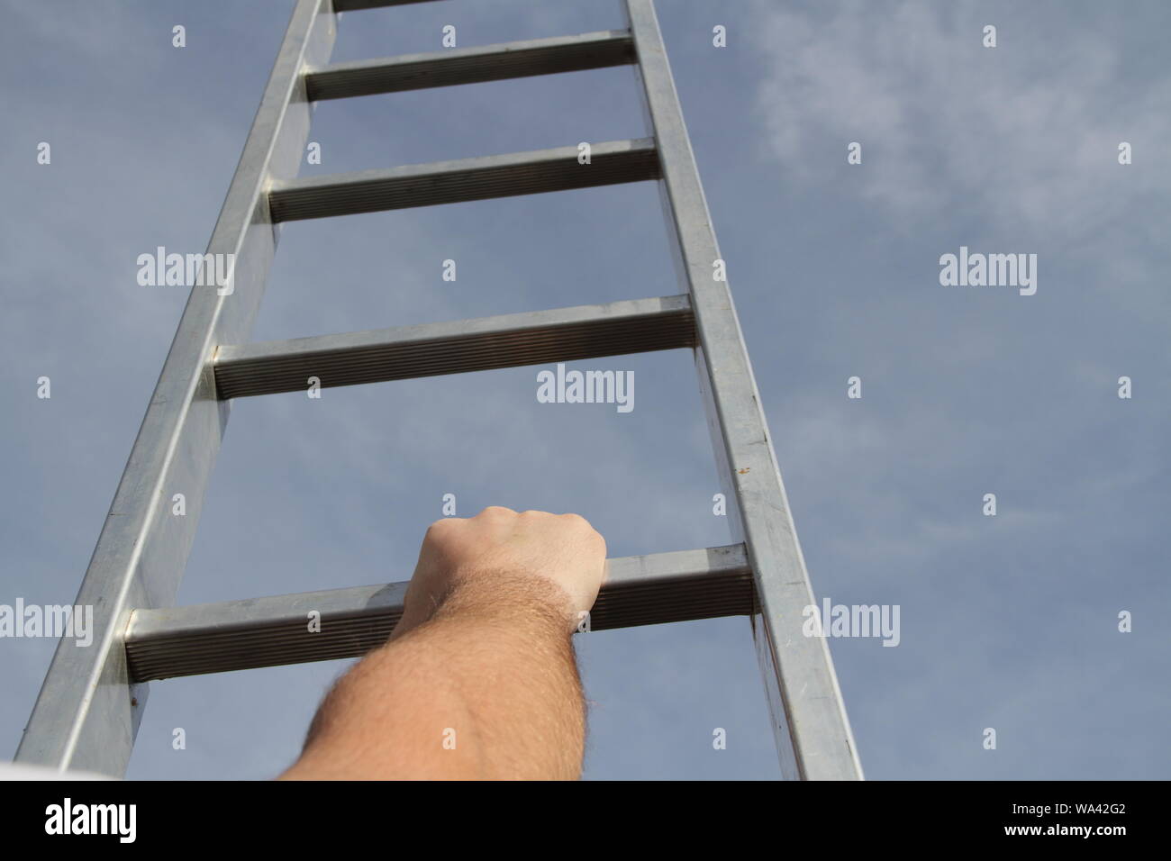 A man is trying to get up the ladder Stock Photo - Alamy