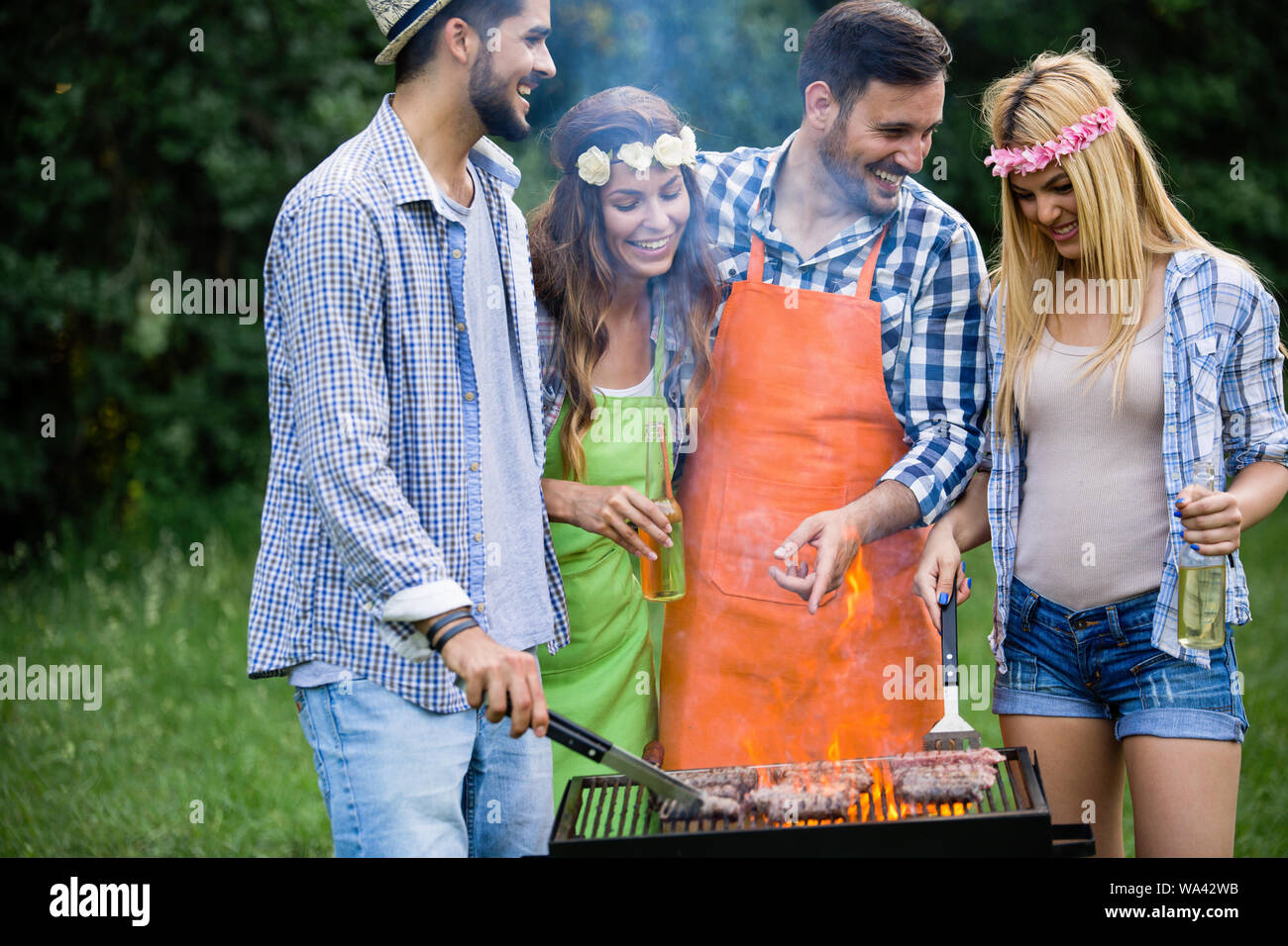 Group of friends making a barbecue together outdoors in the nature ...