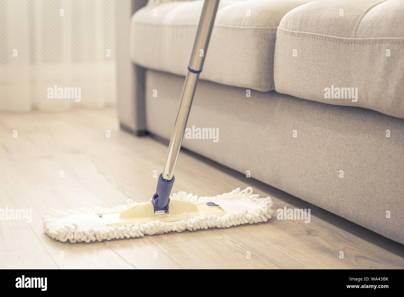 White mop being used for cleaning a wooden floor in modern home Stock ...
