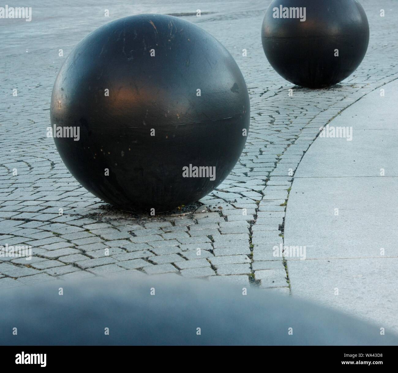 Closeup of black round balls on stony ground Stock Photo - Alamy