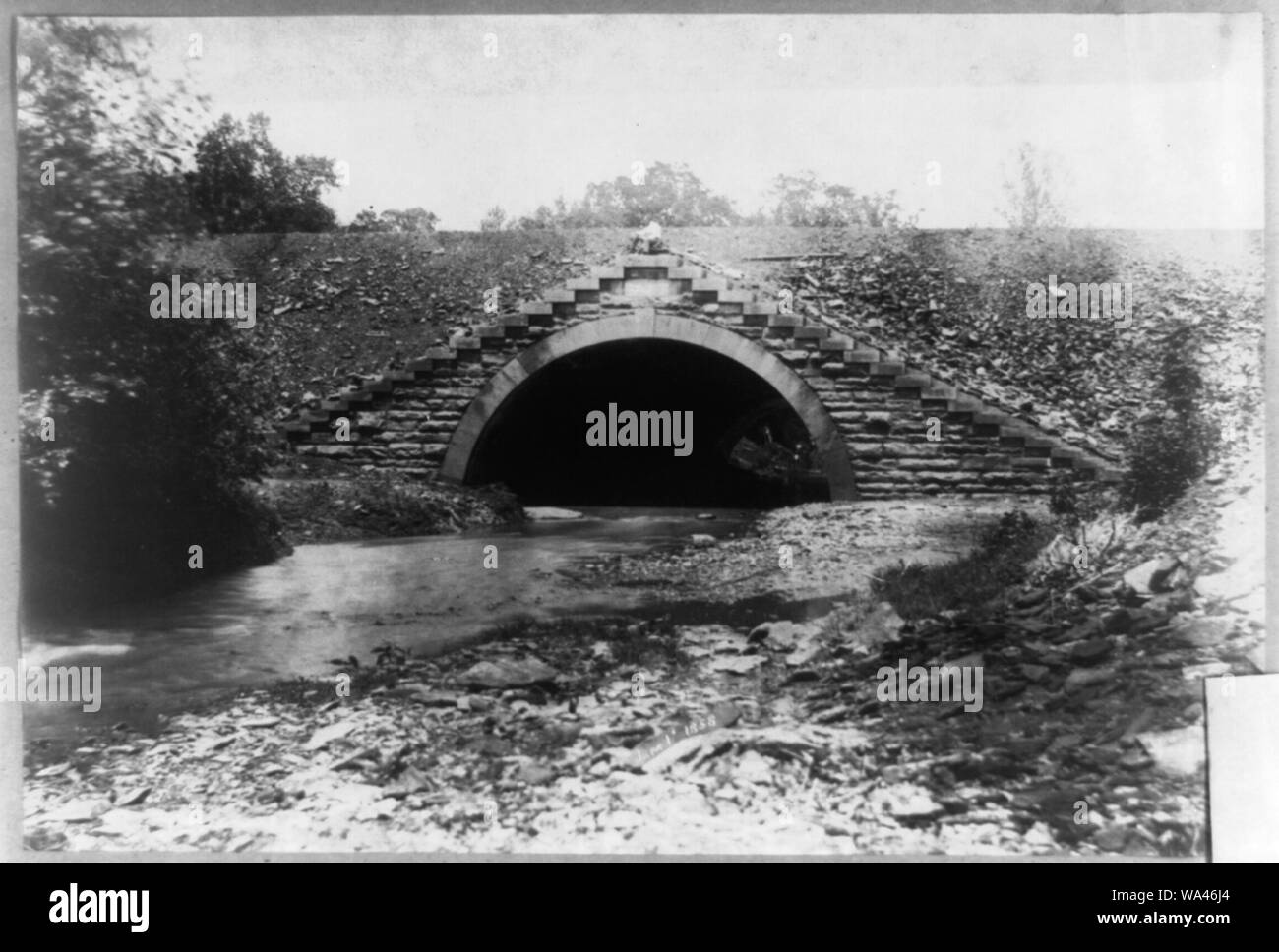 Bridge with man sitting on top, two men standing below Stock Photo - Alamy