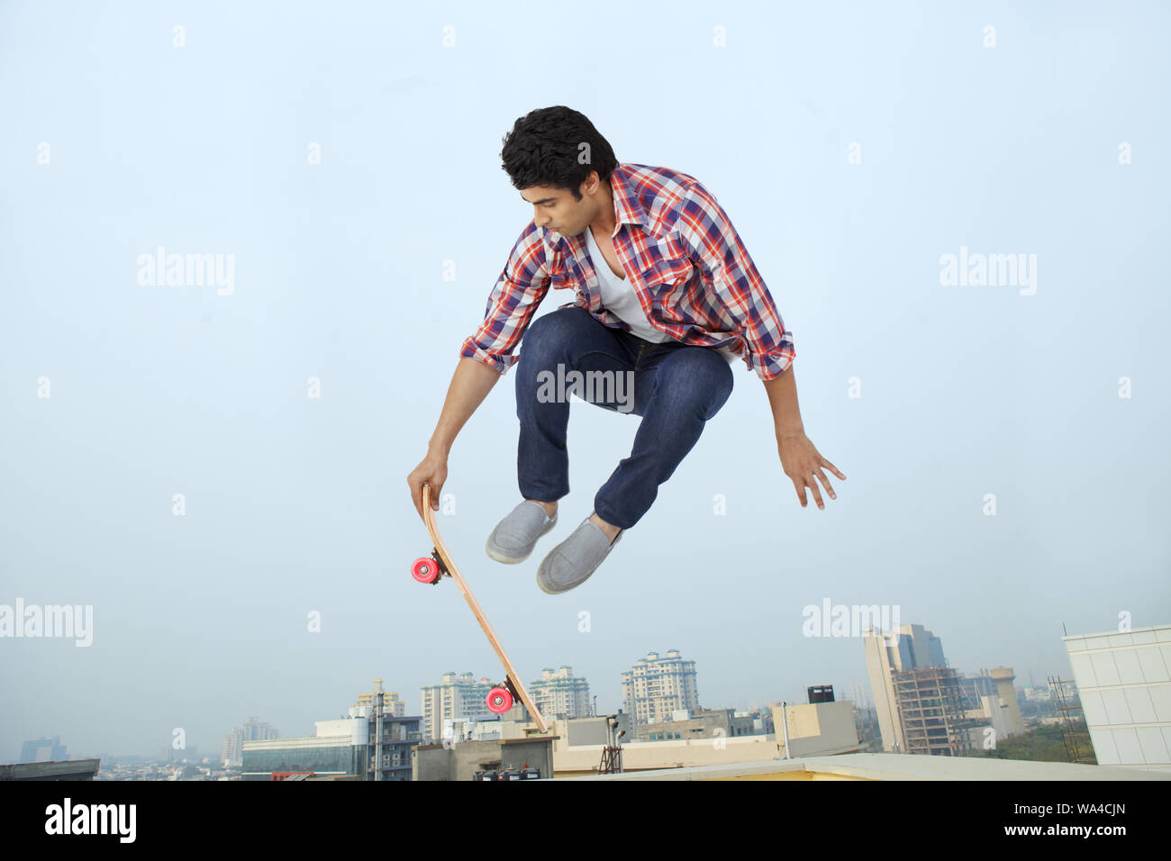 Young man performing jump on skateboard Stock Photo - Alamy