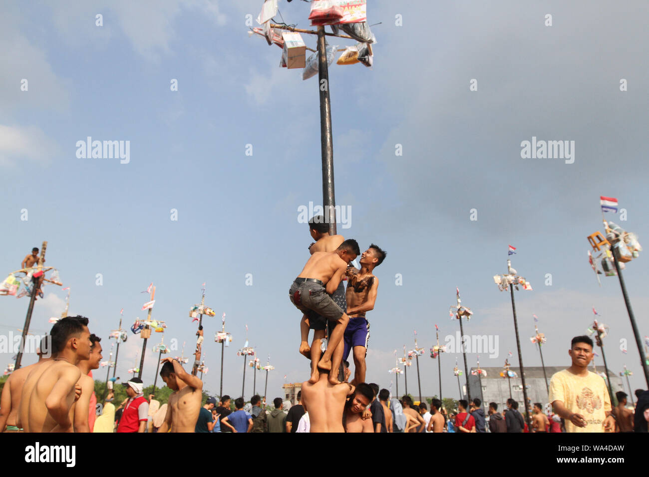 Participants struggling to climb greasy poles during panjat pinang, a ...
