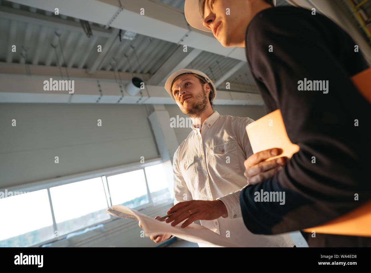 Two building engineers with blueprint working on construction site ...