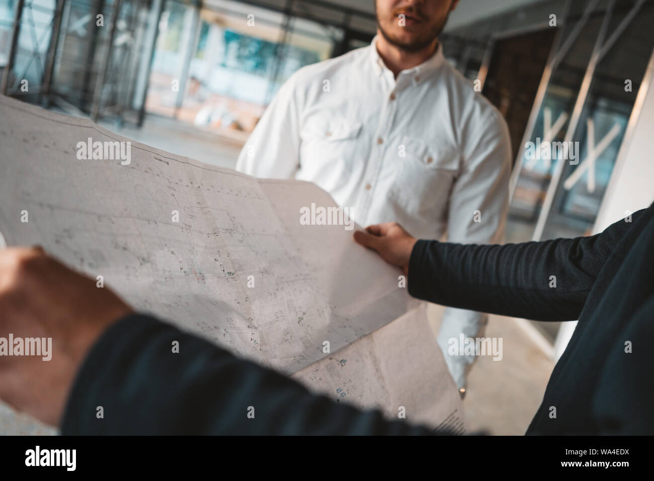 Two building engineers with blueprint working on construction site ...
