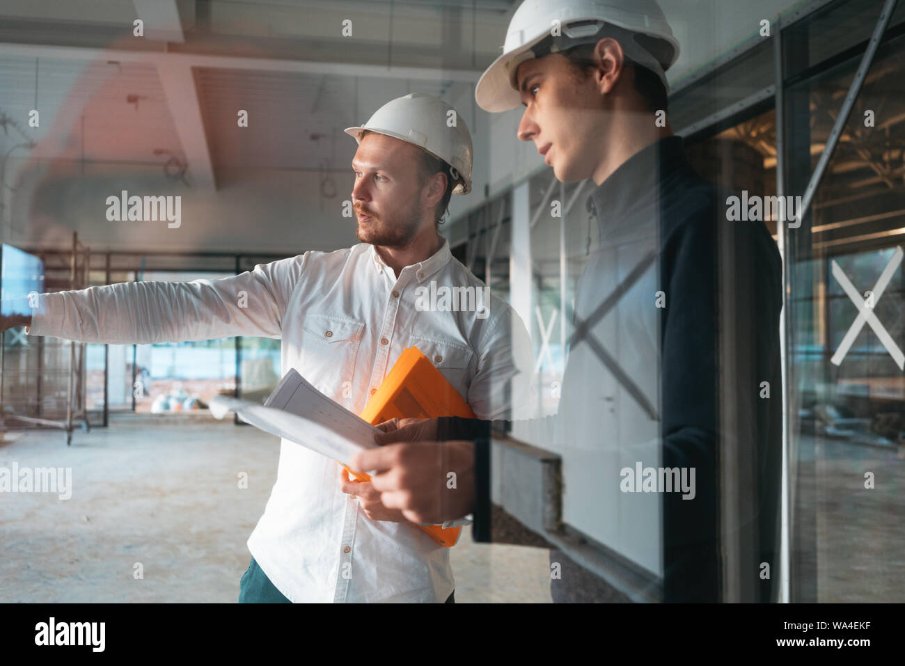 Building inspector hold blueprint in hand and have meeting with worker ...