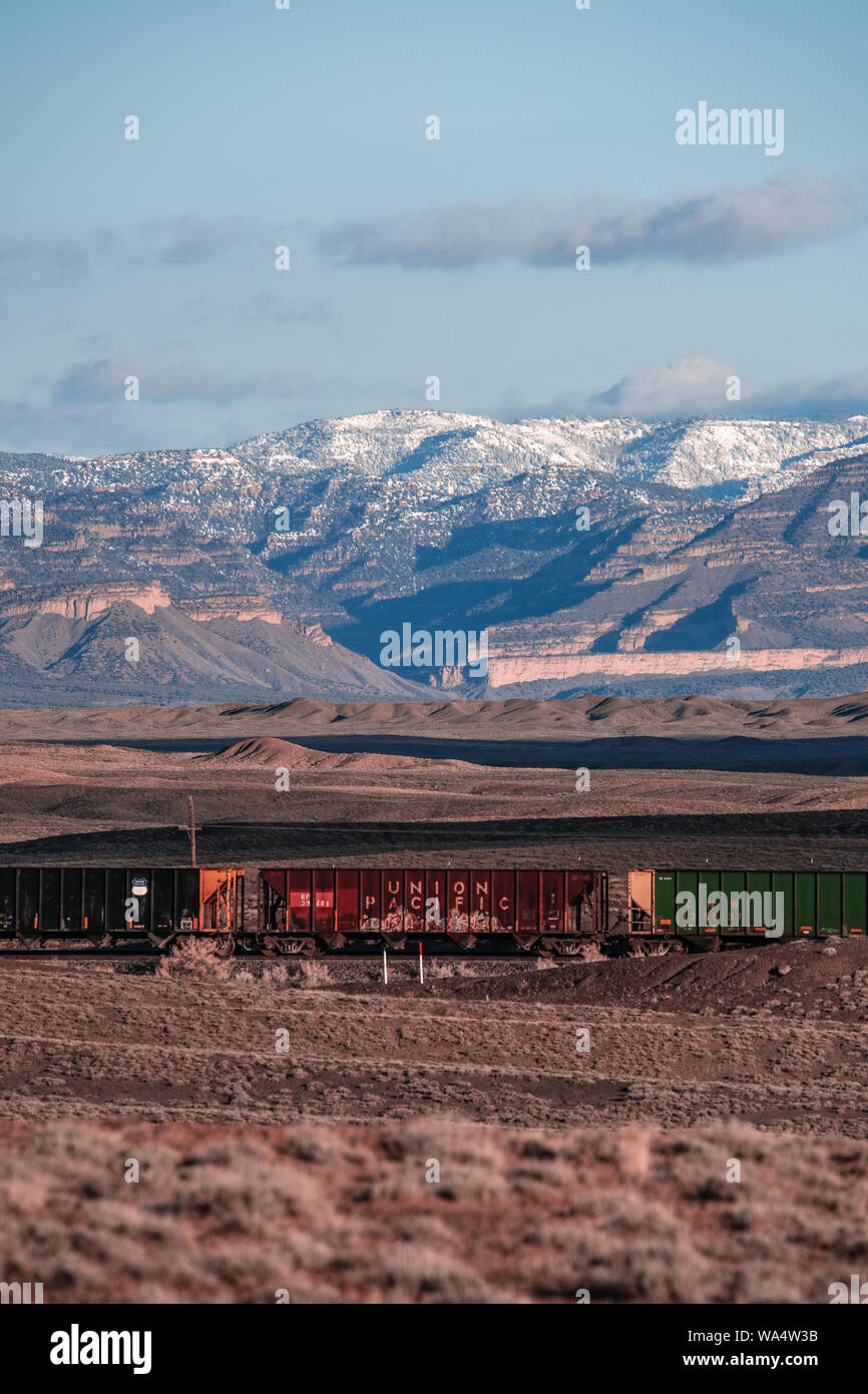 Freight train in rural Utah against a background of mountains and rock ...