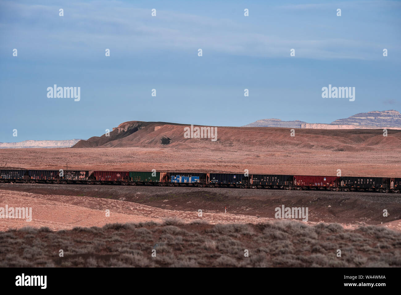 Freight train in rural Utah against a background of mountains and rock ...