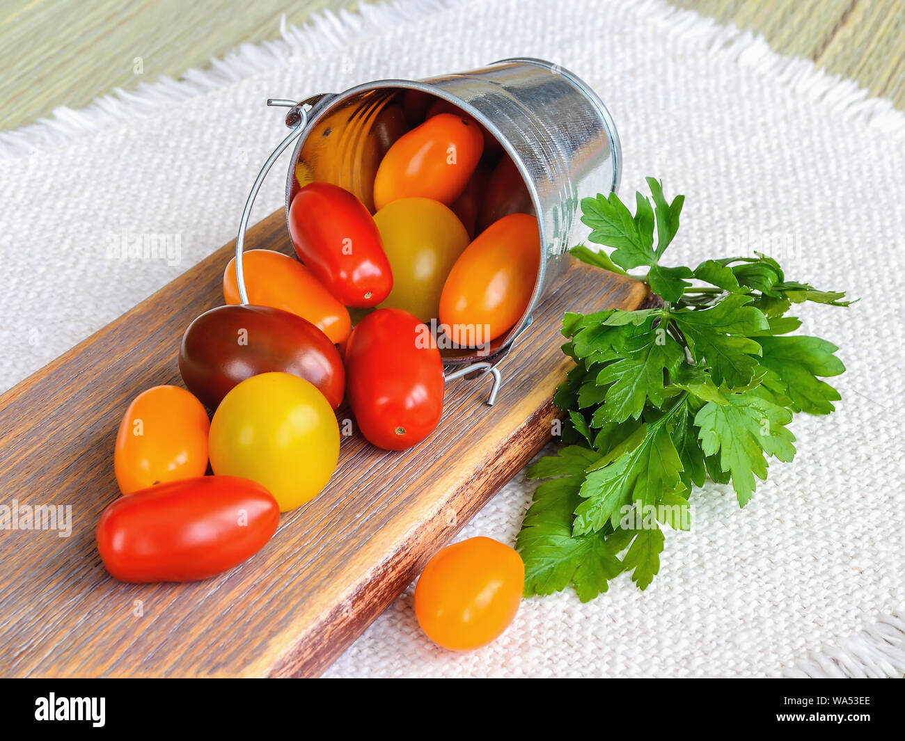 Small fallen bucket with ripe multicolored mini tomatoes and parsley on ...