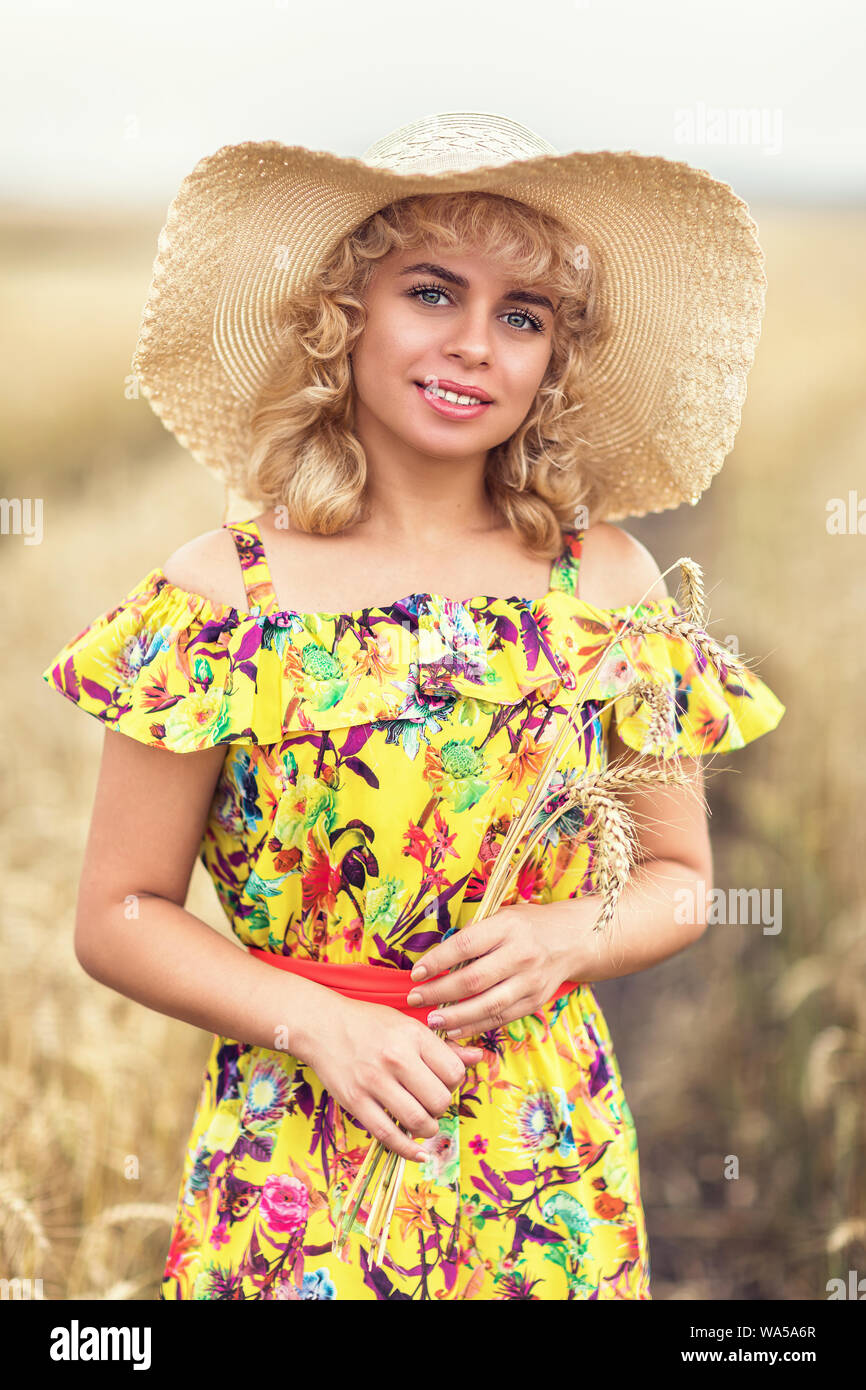Portrait of a beautiful girl in a hat holding ripe spikelets of barley ...