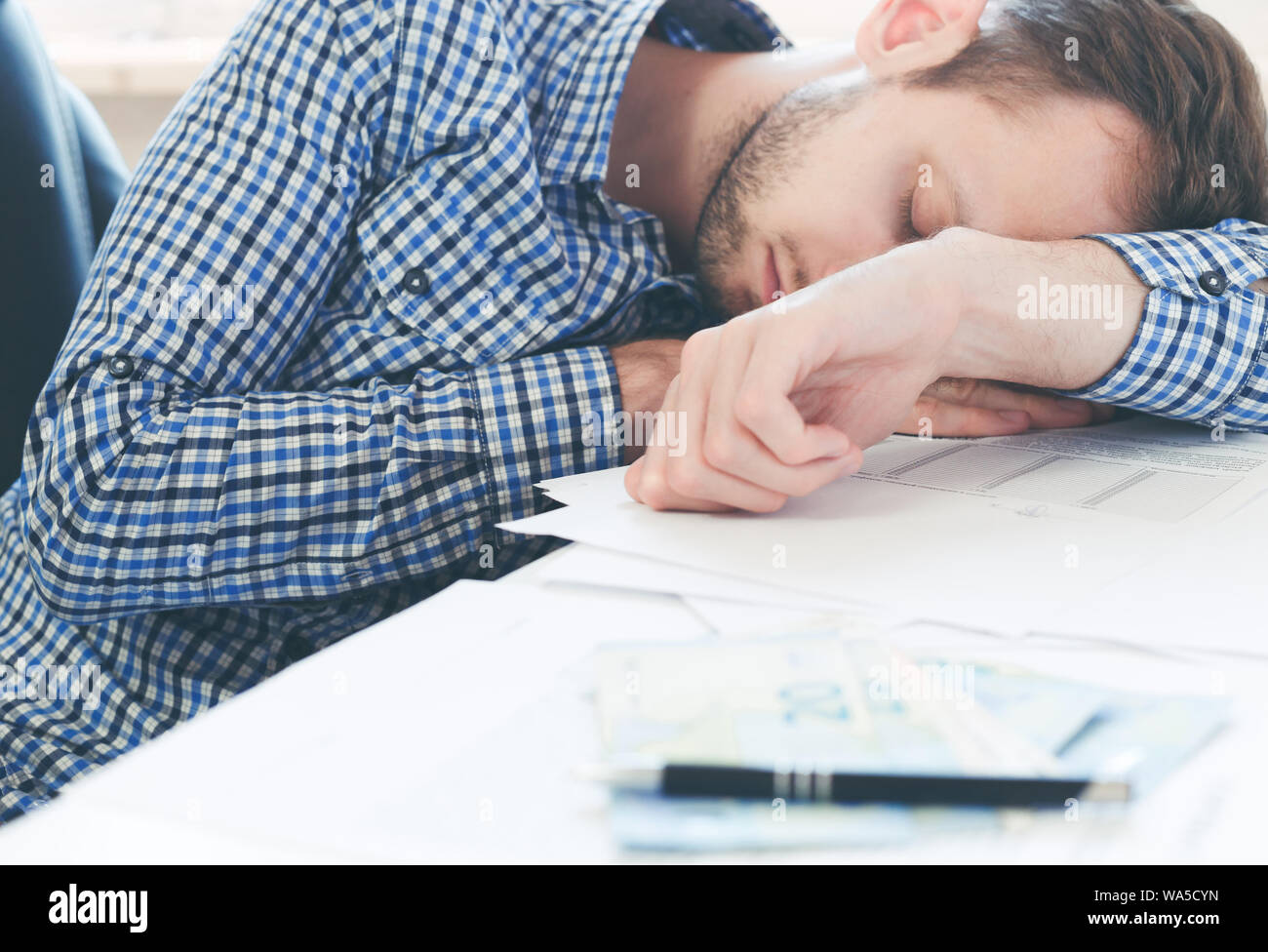 Overworked and tired office worker sleeping over at work on table in ...