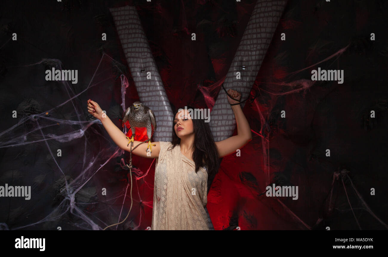 beauty brunette girl and a hawk on dark gothic scary studio background ...