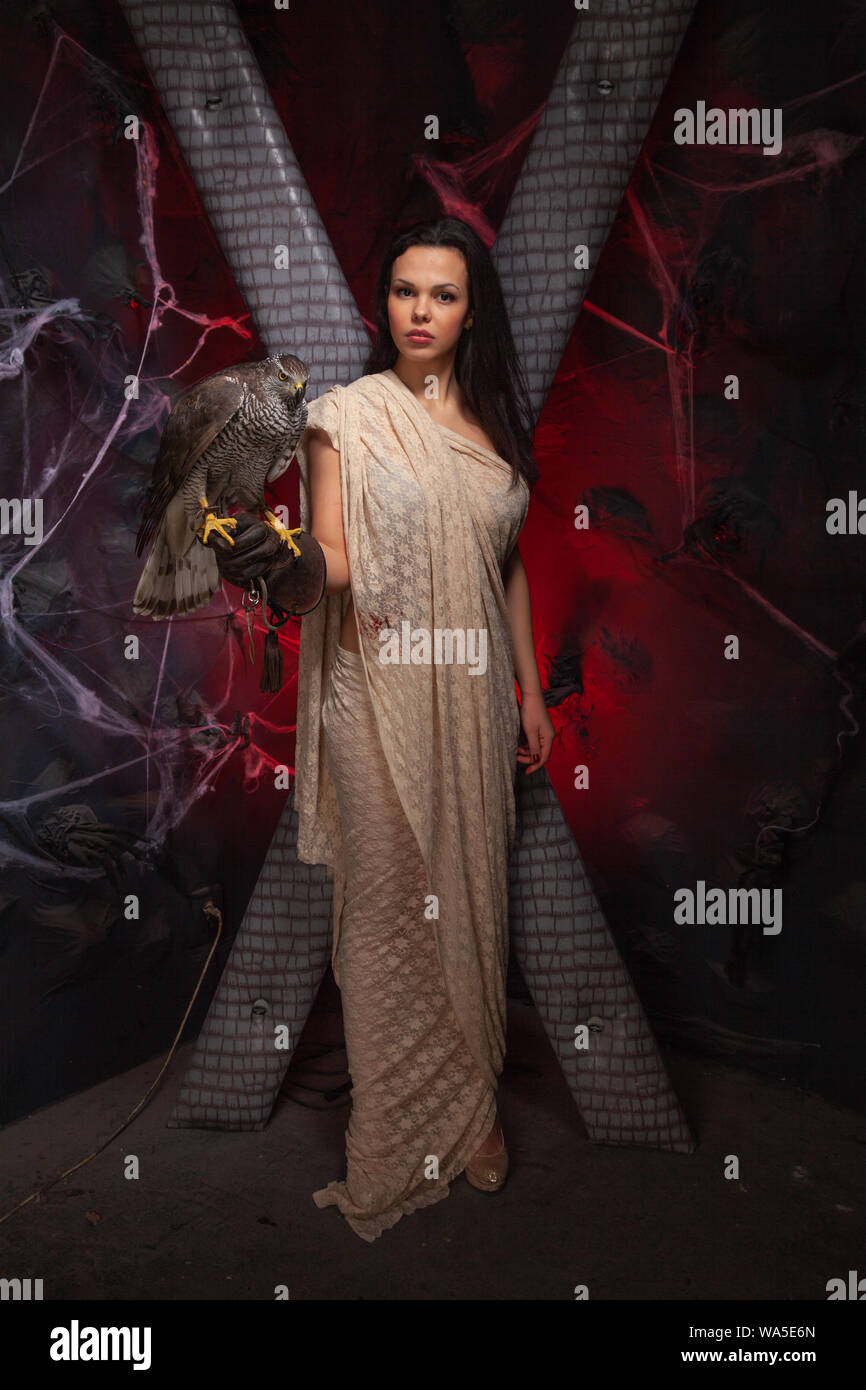 beauty brunette girl and a hawk on dark gothic scary studio background ...