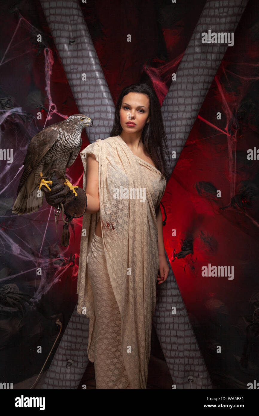beauty brunette girl and a hawk on dark gothic scary studio background ...