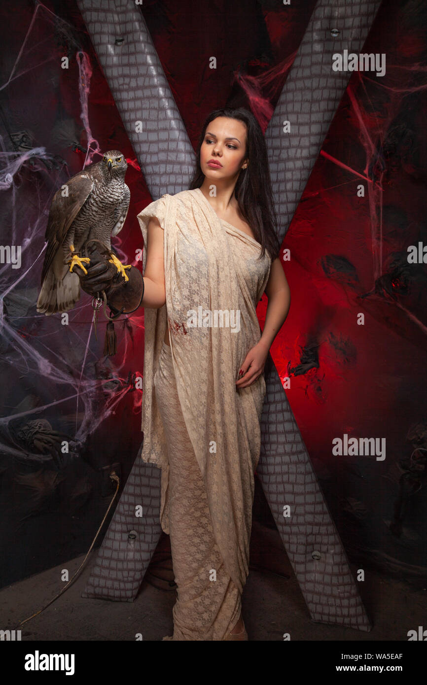 beauty brunette girl and a hawk on dark gothic scary studio background ...