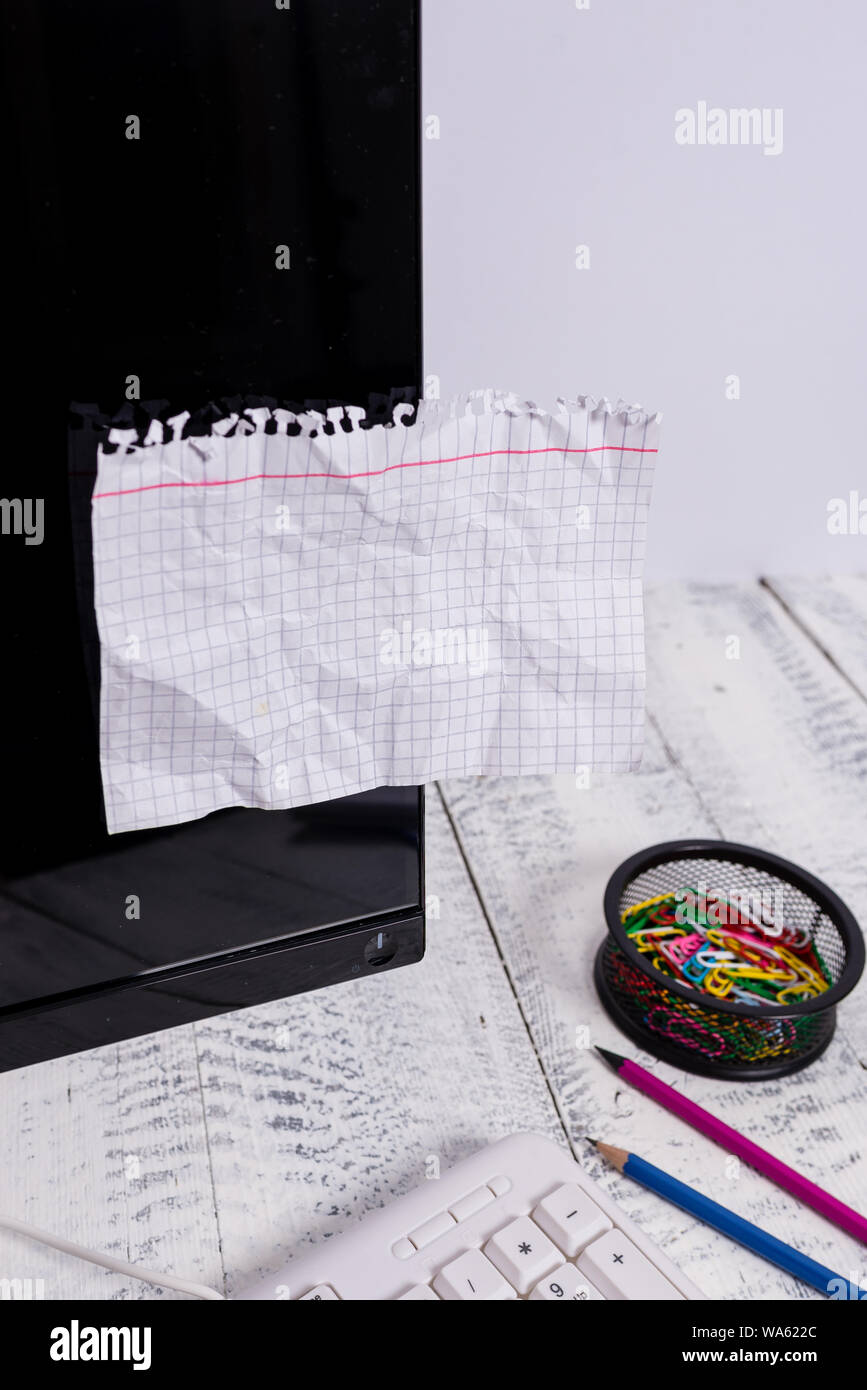 Note paper taped to black computer screen near keyboard and stationary ...