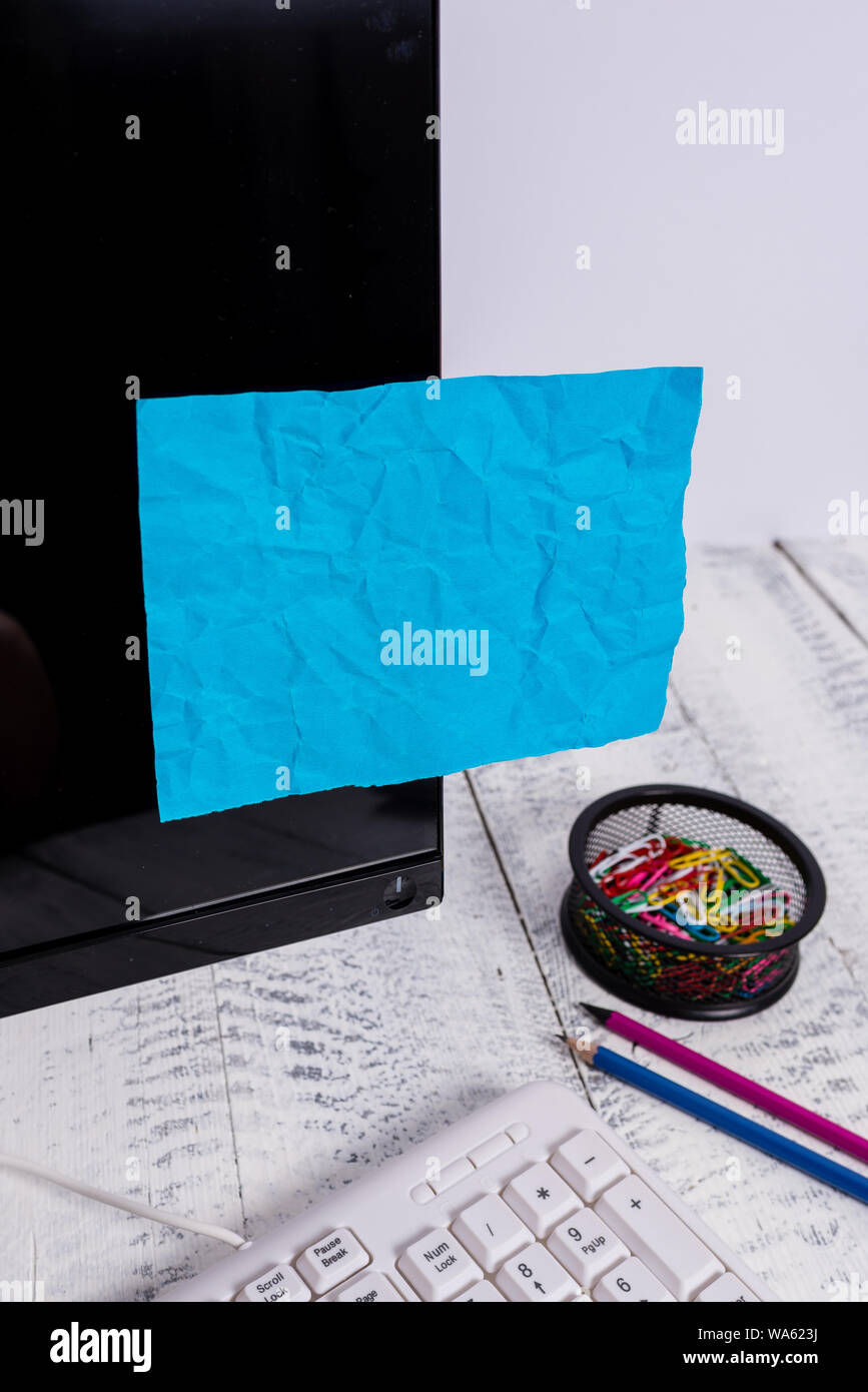 Note paper taped to black computer screen near keyboard and stationary ...