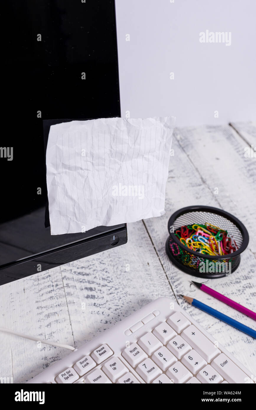 Note paper taped to black computer screen near keyboard and stationary ...