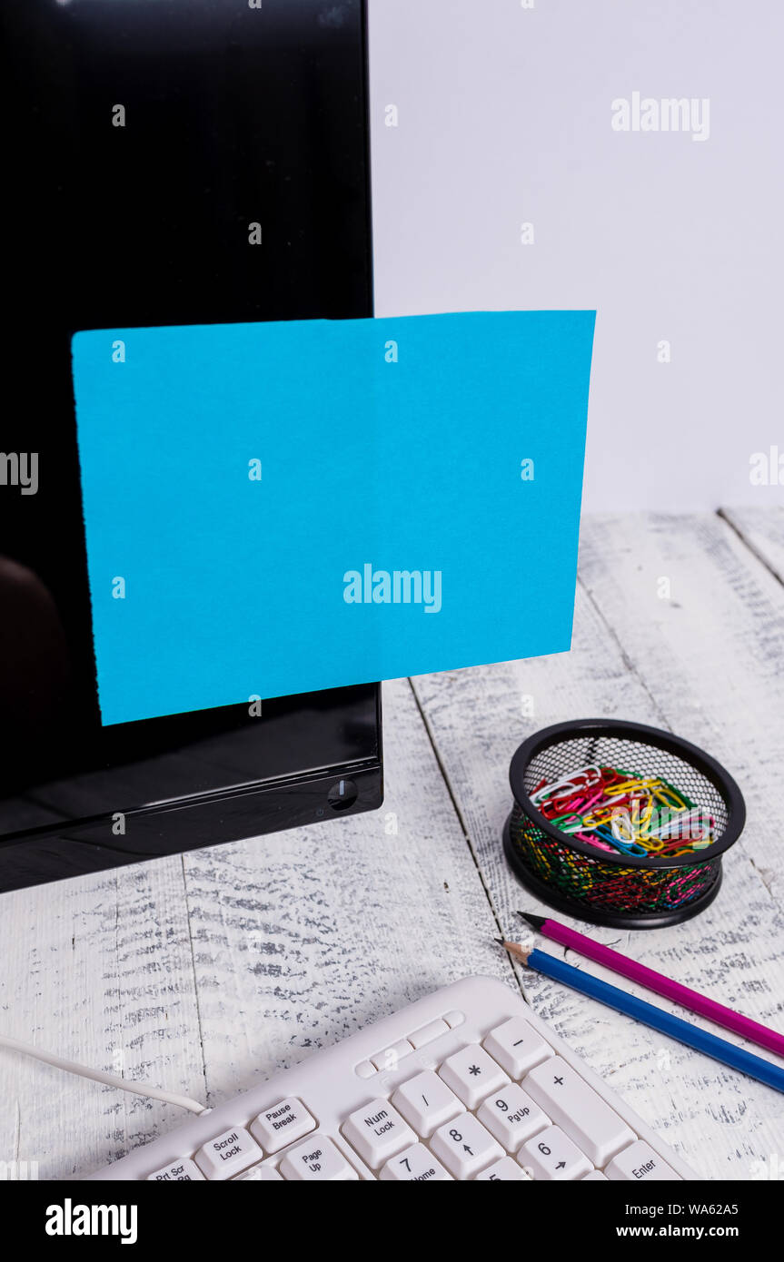 Note paper taped to black computer screen near keyboard and stationary ...