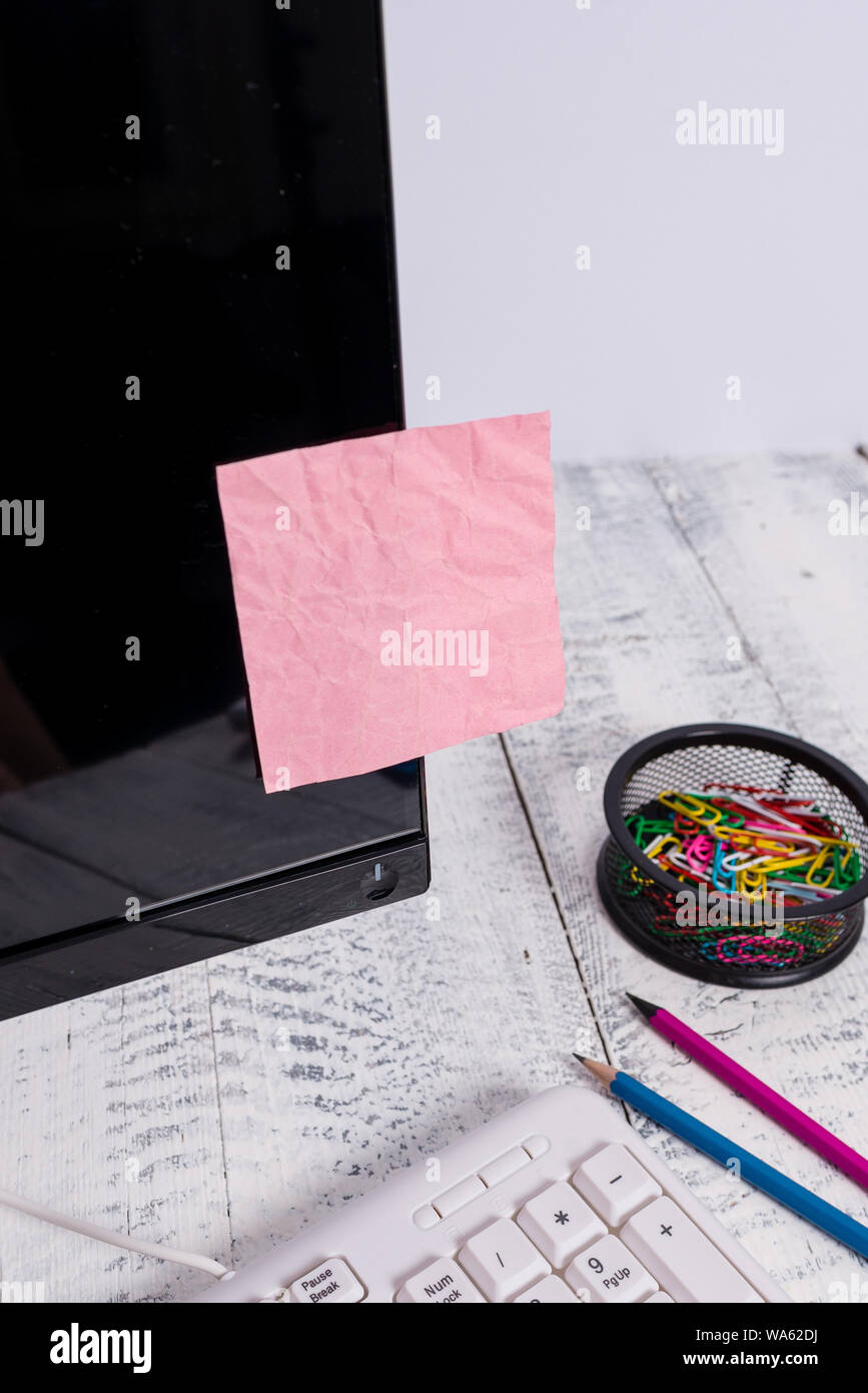 Note paper taped to black computer screen near keyboard and stationary ...