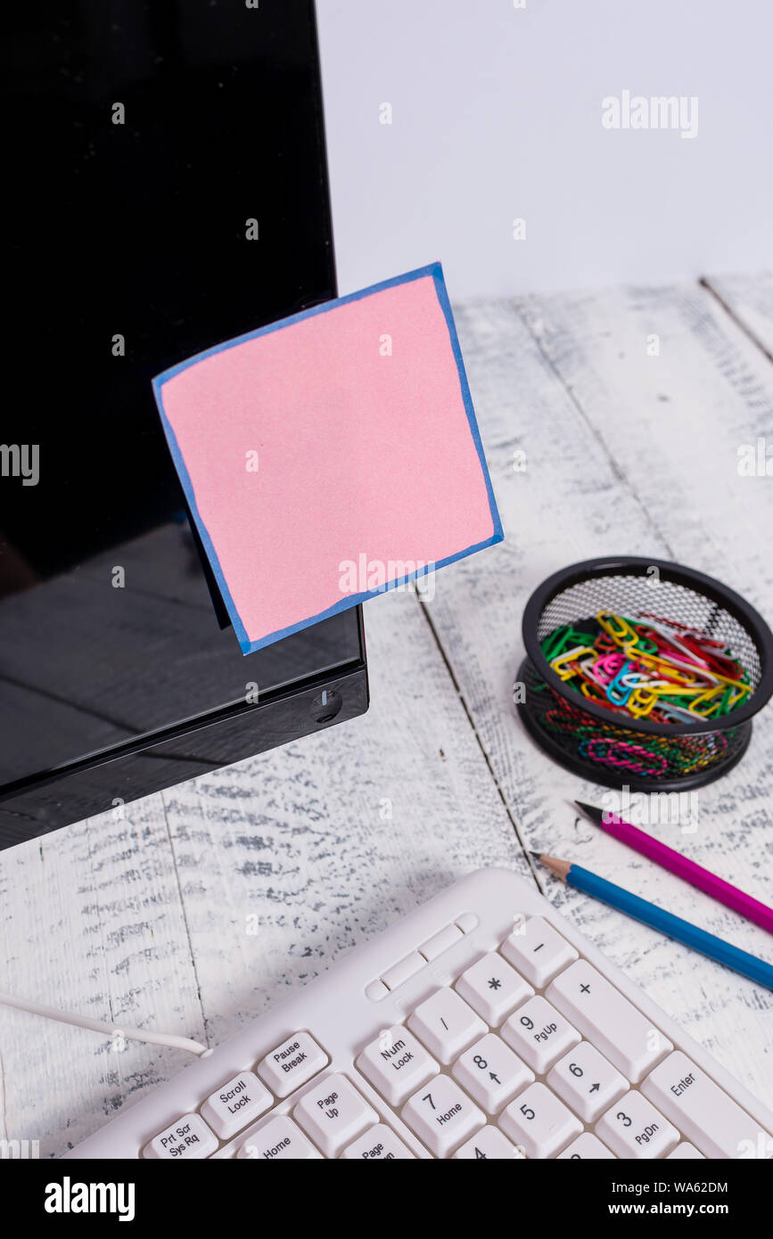 Note paper taped to black computer screen near keyboard and stationary ...