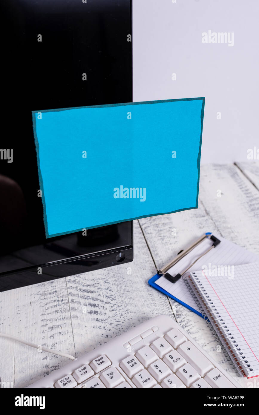 Note paper taped to black computer screen near keyboard and stationary ...