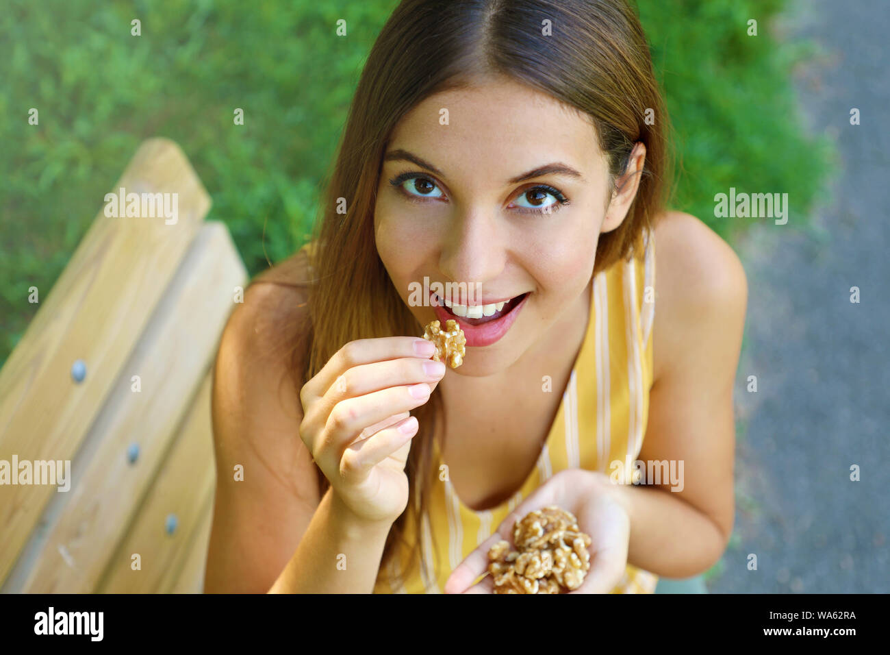 Close up view from above of a woman eating walnuts outdoors. Healthy ...