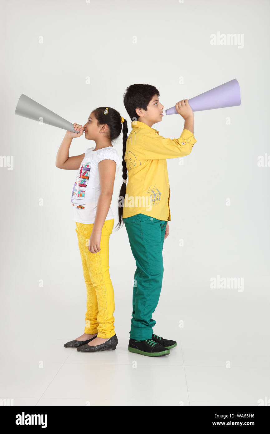 Two friends shouting into paper megaphones Stock Photo - Alamy
