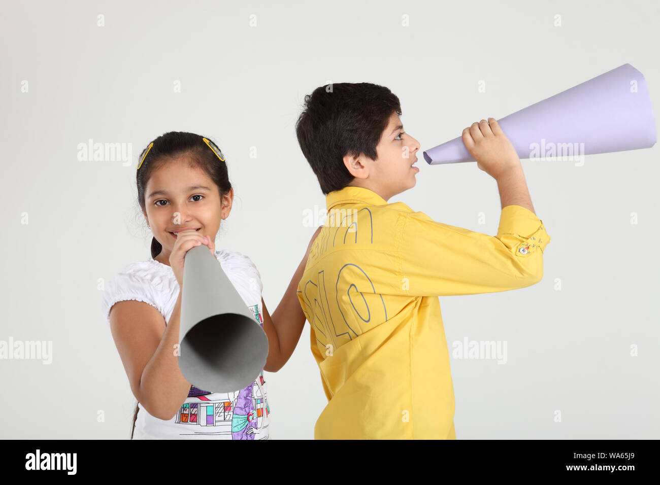 Two friends shouting into paper megaphones Stock Photo - Alamy