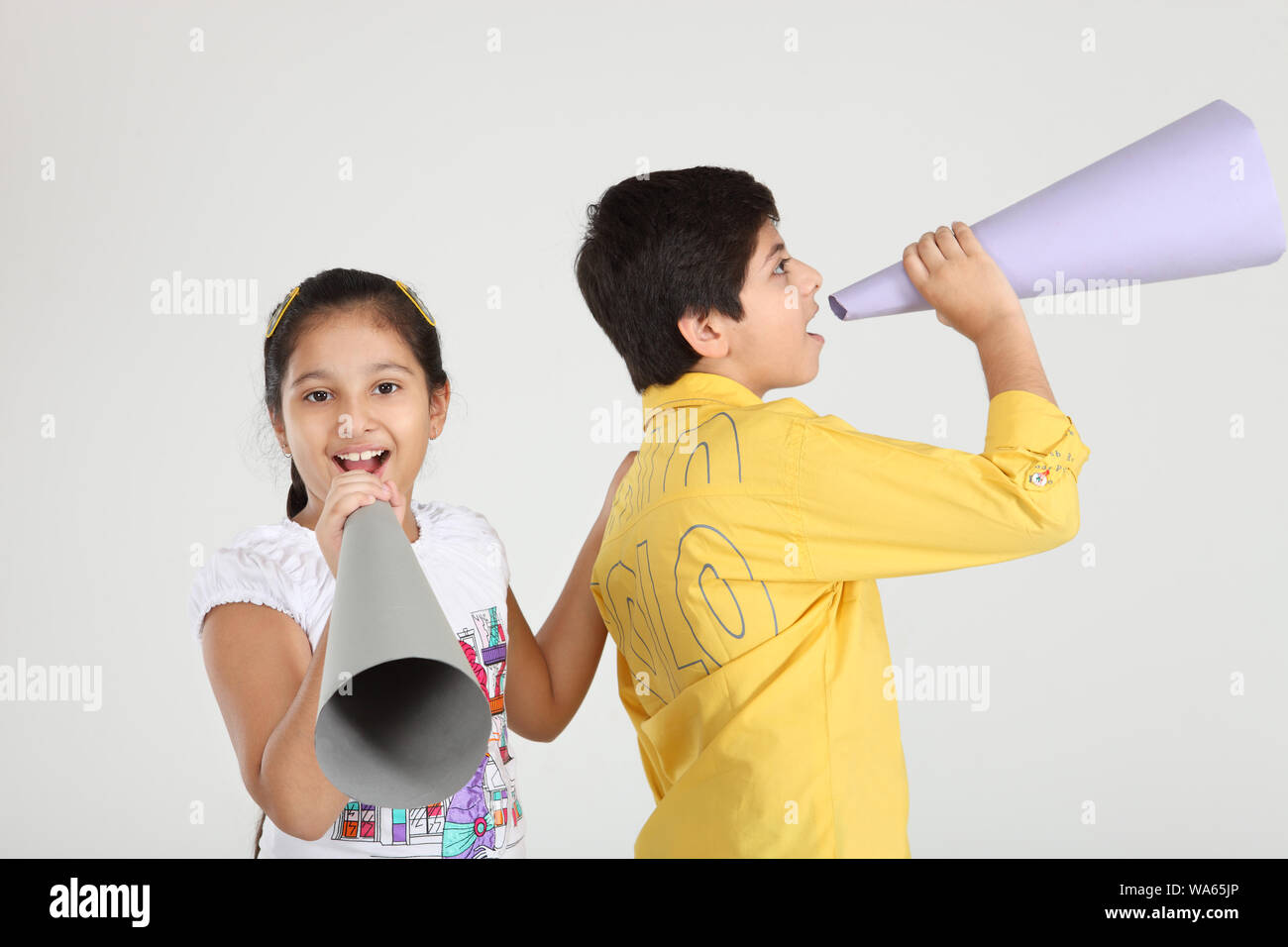 Two friends shouting into paper megaphones Stock Photo - Alamy