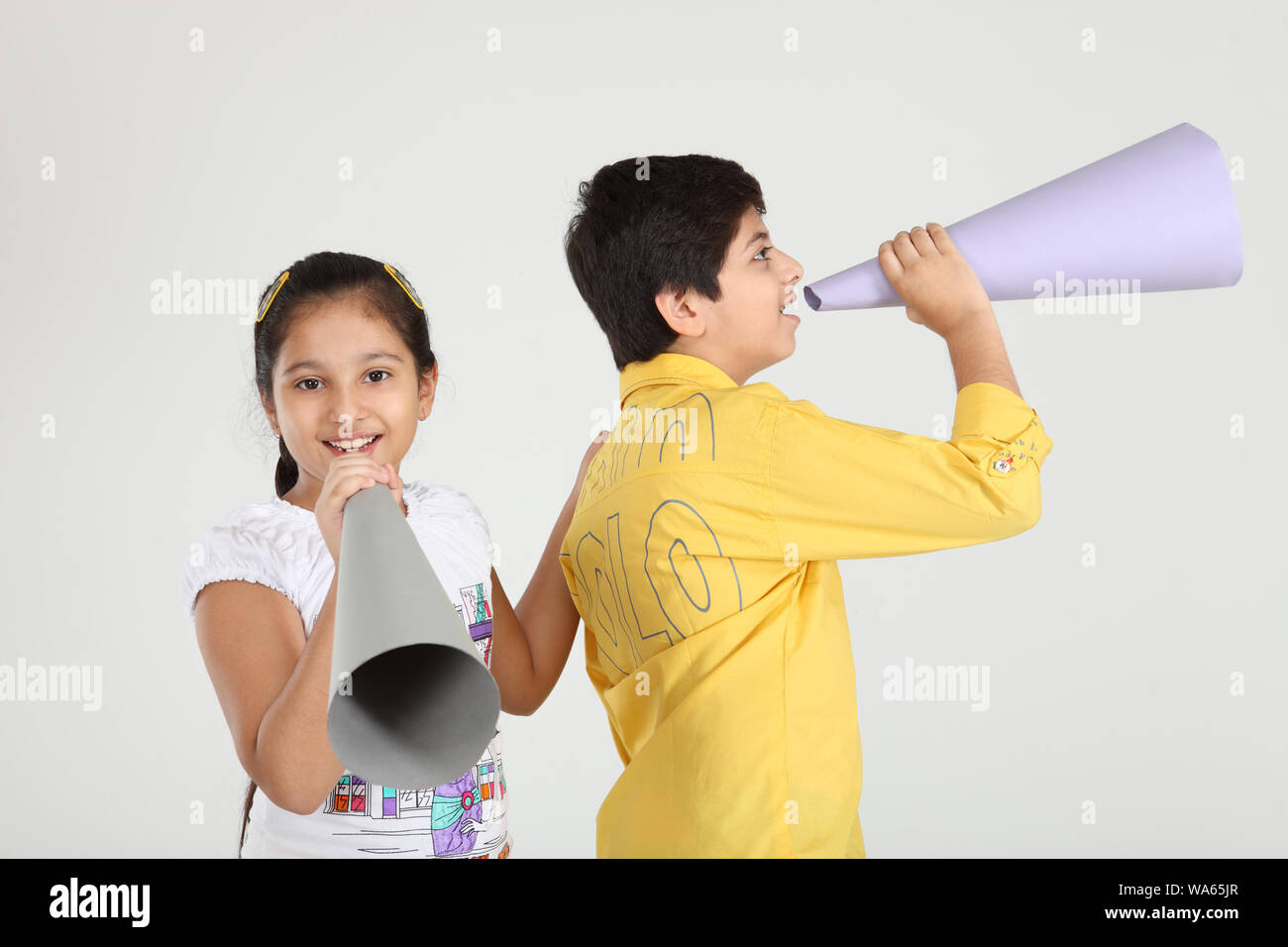 Two friends shouting into paper megaphones Stock Photo - Alamy