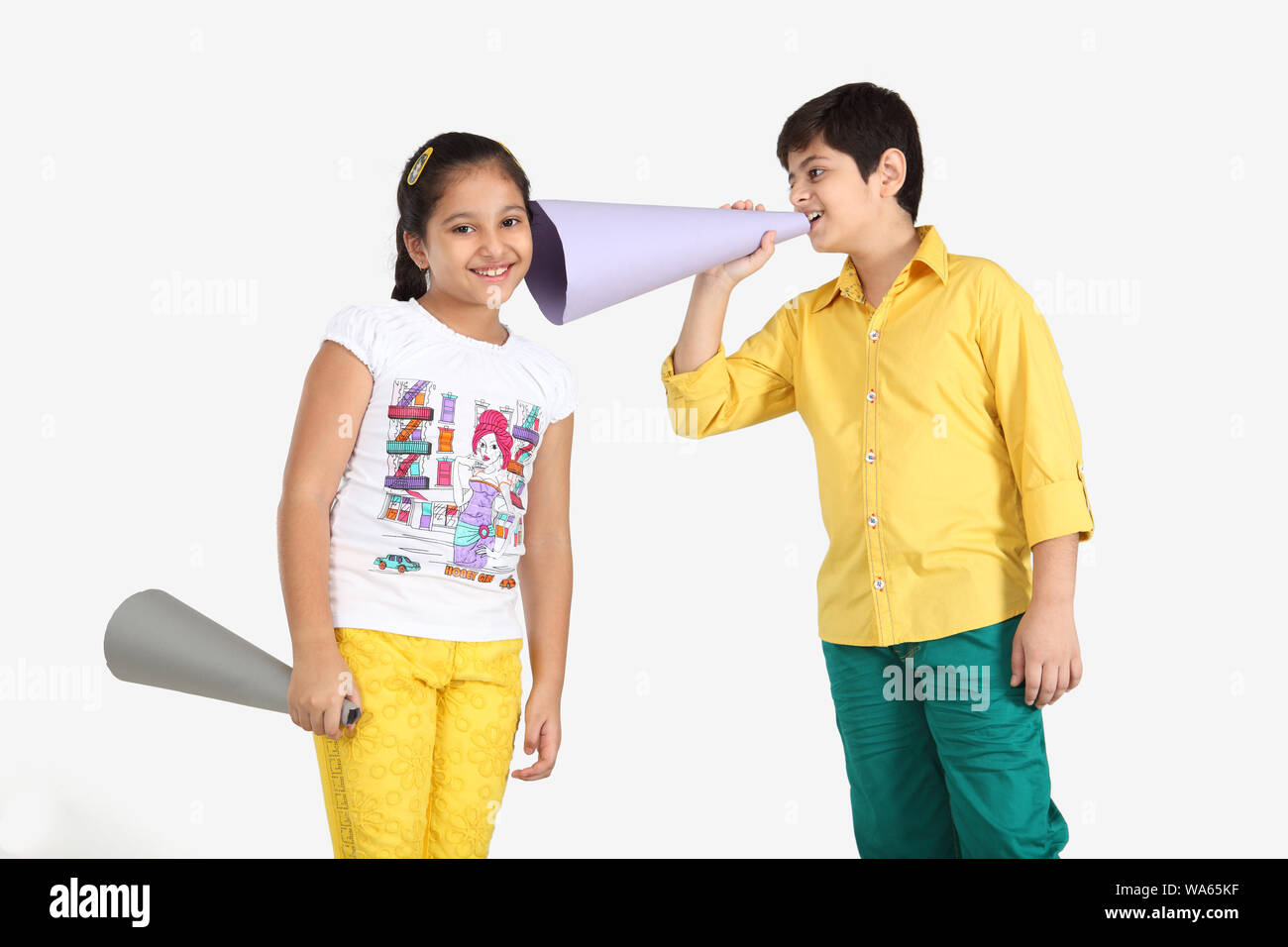 Boy shouting into friend,s ear through megaphone Stock Photo - Alamy