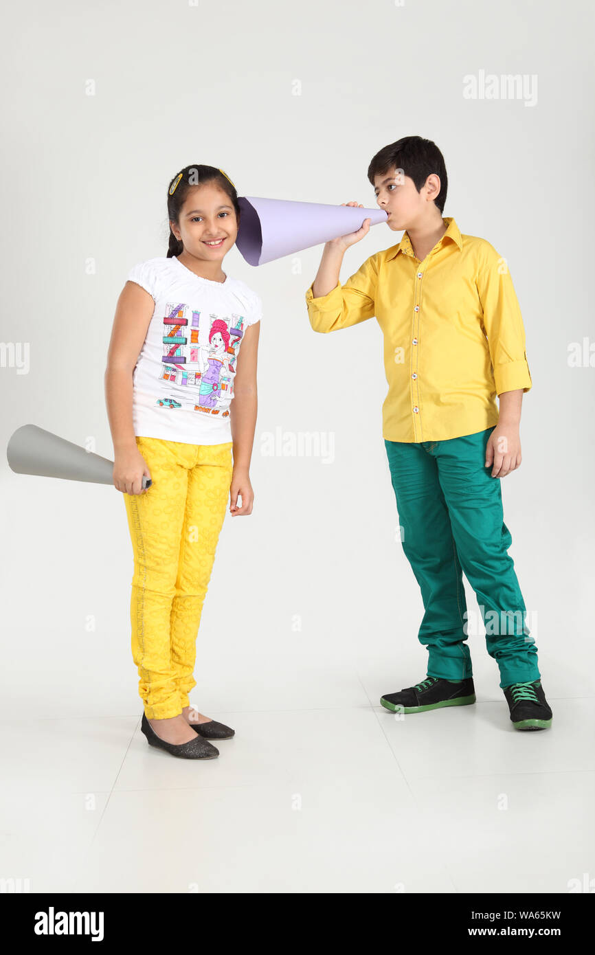 Boy shouting into friend,s ear through megaphone Stock Photo - Alamy
