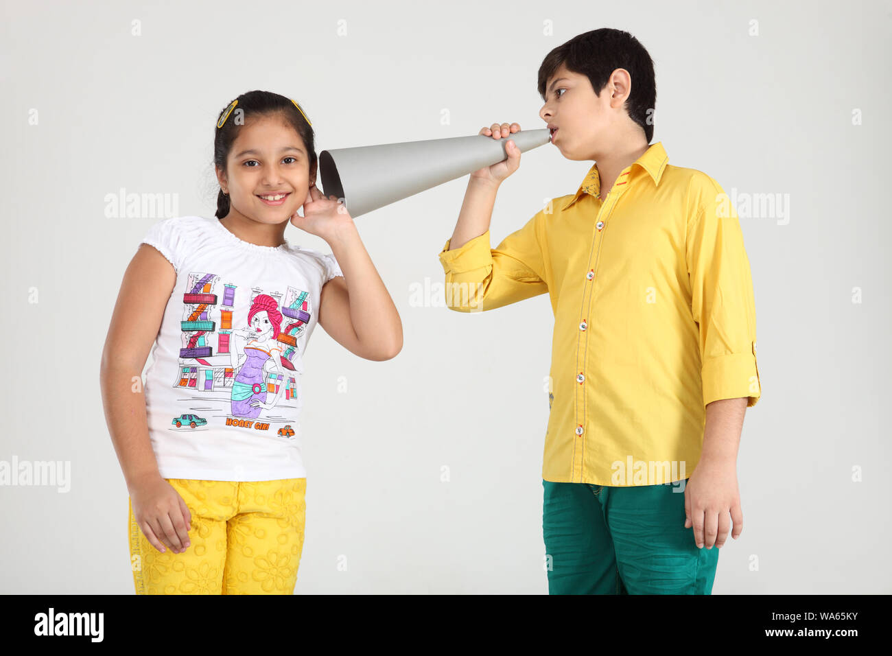 Boy shouting into friend,s ear through megaphone Stock Photo - Alamy