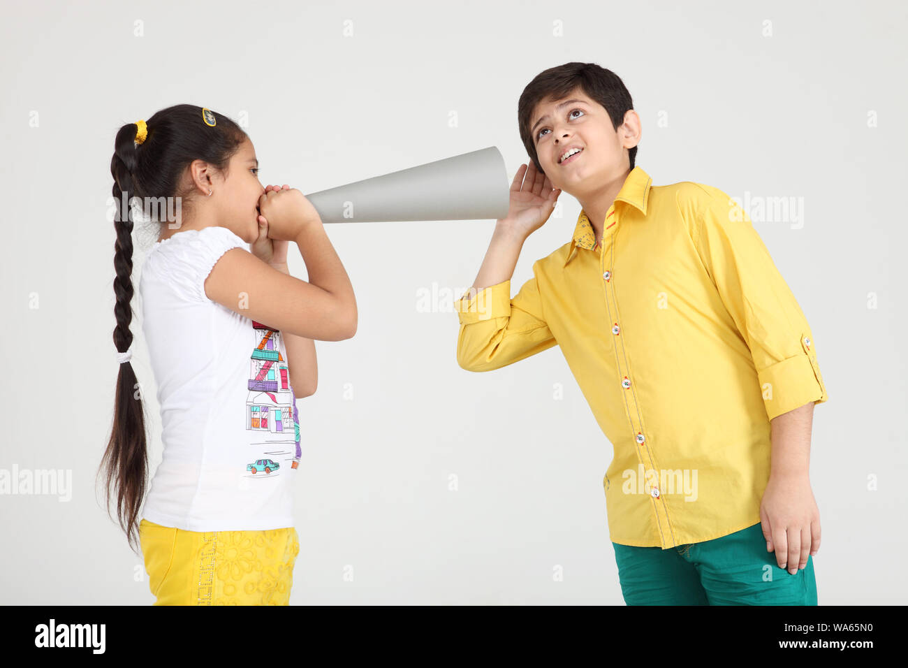 Girl shouting into friend,s ear through megaphone Stock Photo - Alamy
