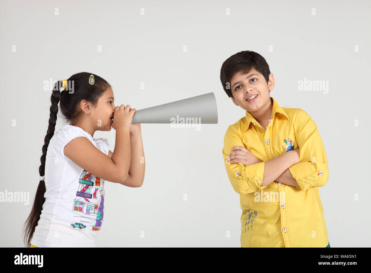 Girl shouting into friend ear through megaphone Stock Photo - Alamy