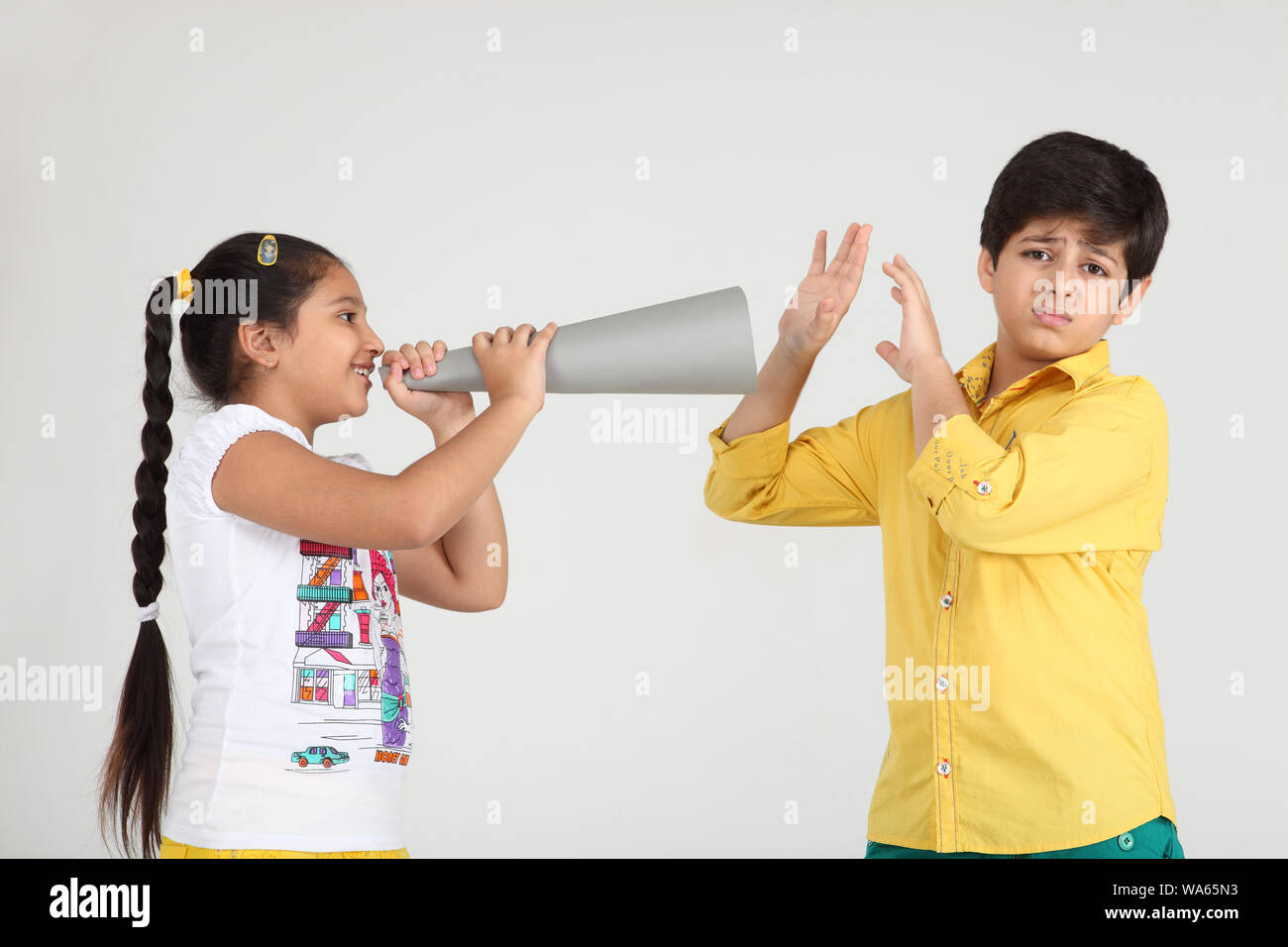 Girl shouting into friend ear through megaphone Stock Photo - Alamy