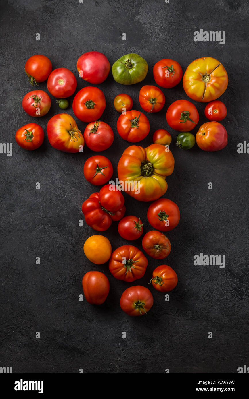 Letter T made with ripe tomatoes on a black background, creative flat ...