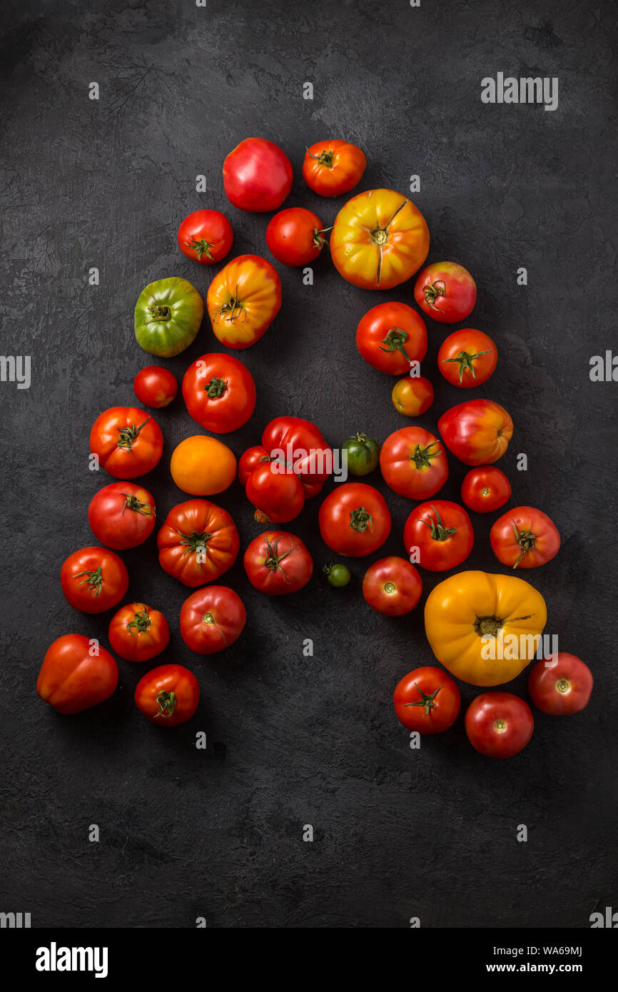 Letter A made with ripe tomatoes on a black background, creative flat ...