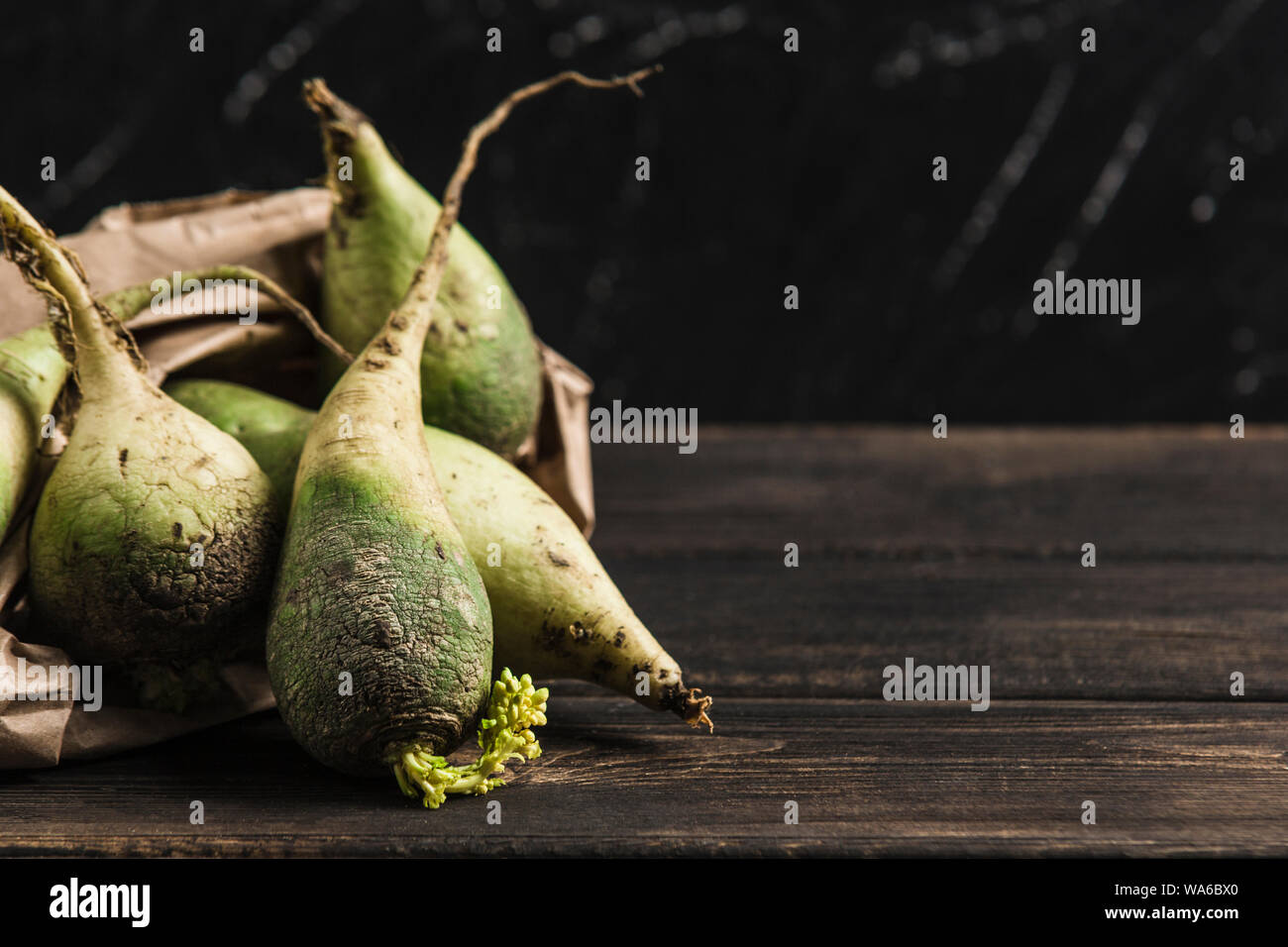 Ugly vegetable green radish with sprouts on a dark wooden natural ...