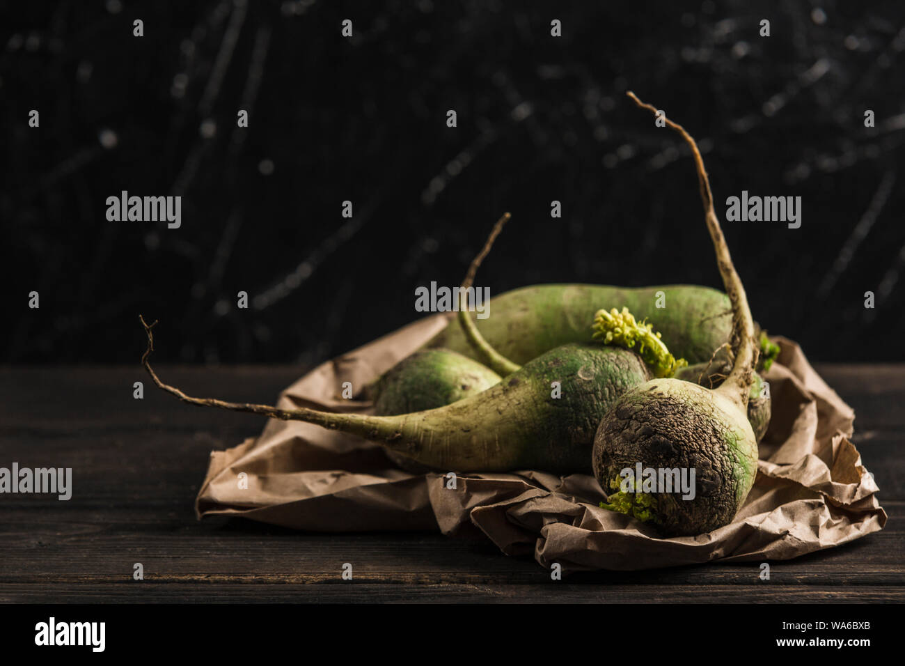 Ugly vegetable green radish with sprouts on a dark wooden natural ...