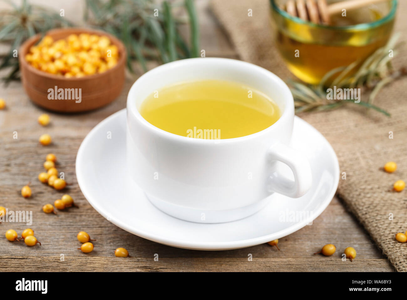 fresh sea buckthorn tea on a simple wooden background in a small plate ...