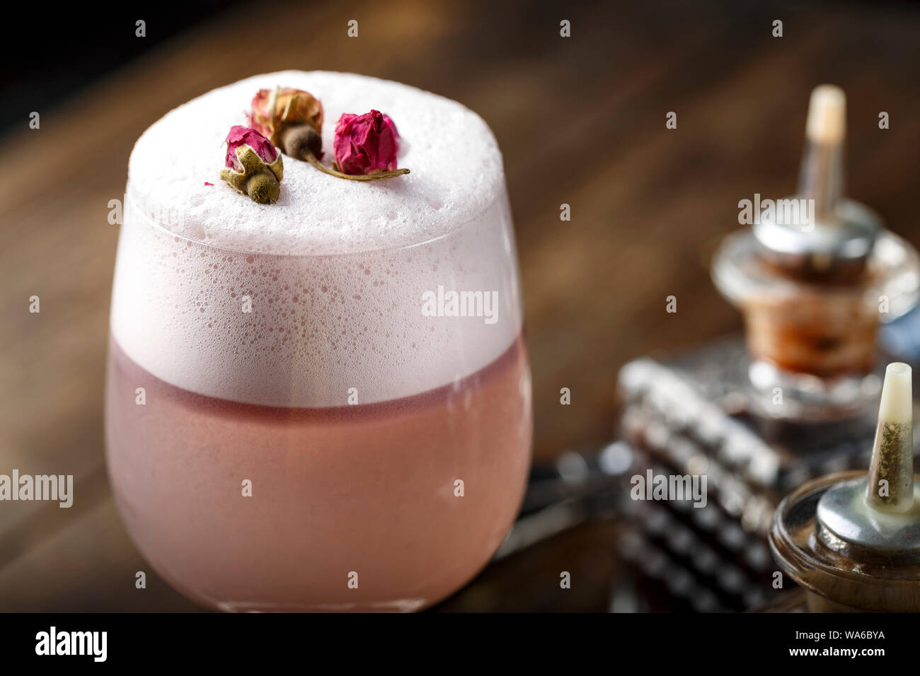 Pink alcoholic cocktail with foam, decorated with dry roses. drink on ...