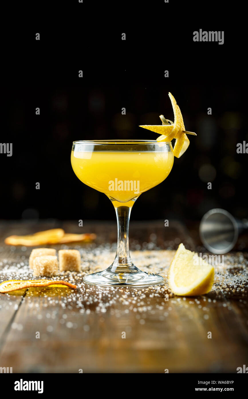 beautiful yellow alcoholic cocktail, decorated with orange peel. on a ...