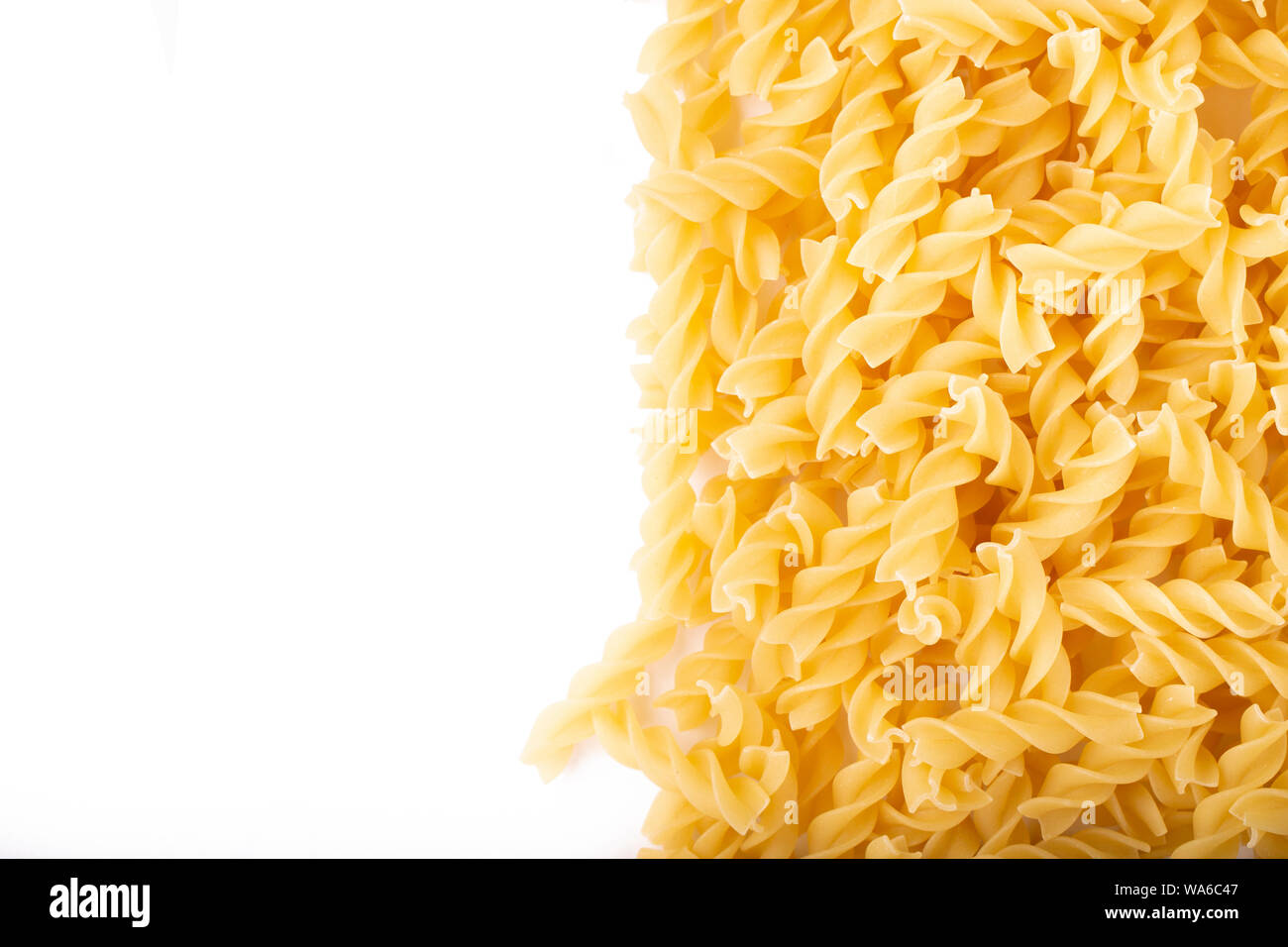 raw spiral pasta scattered on a white background. traditional italian ...