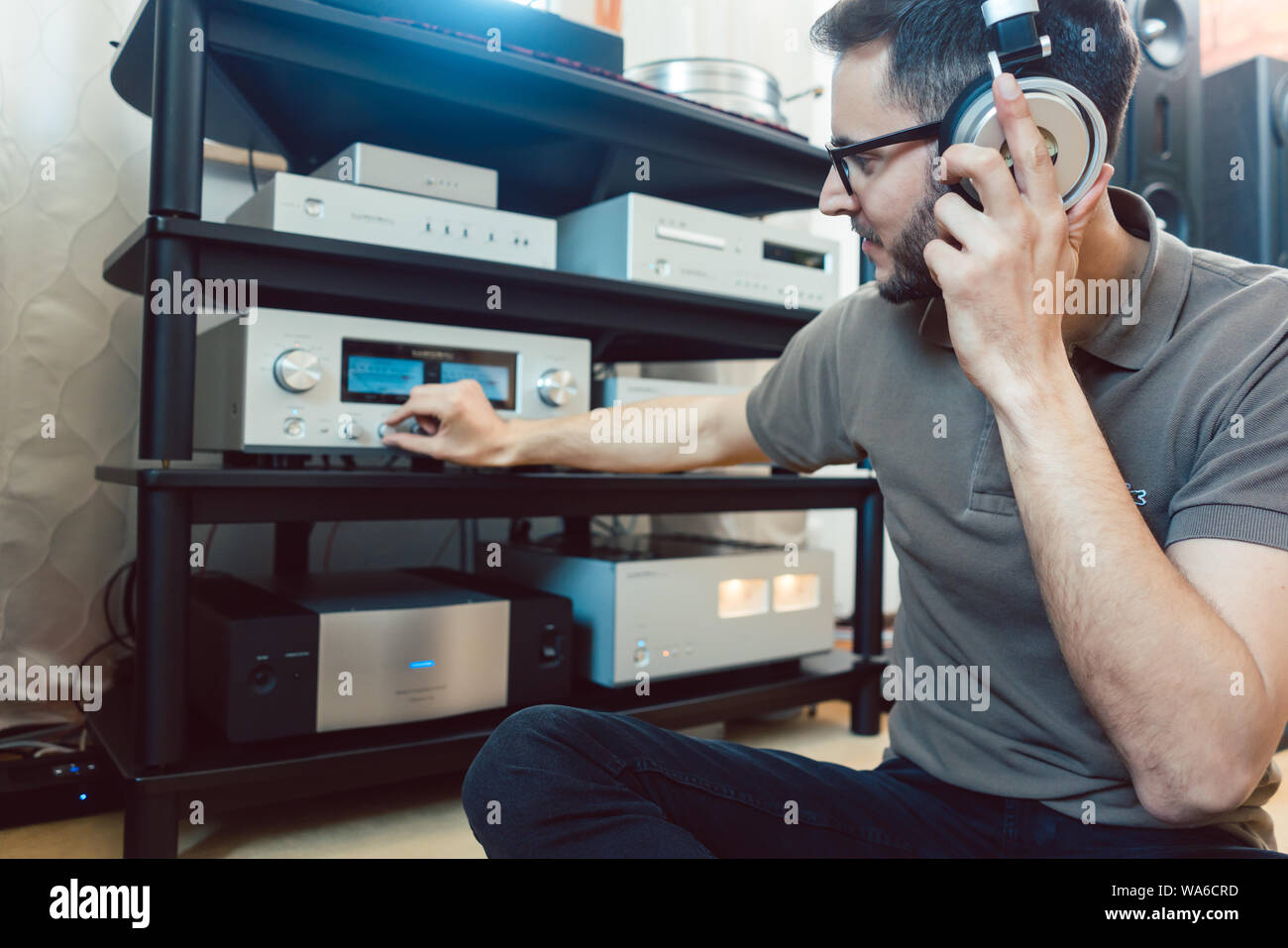 Man turning up the volume on home Hi-Fi stereo Stock Photo - Alamy