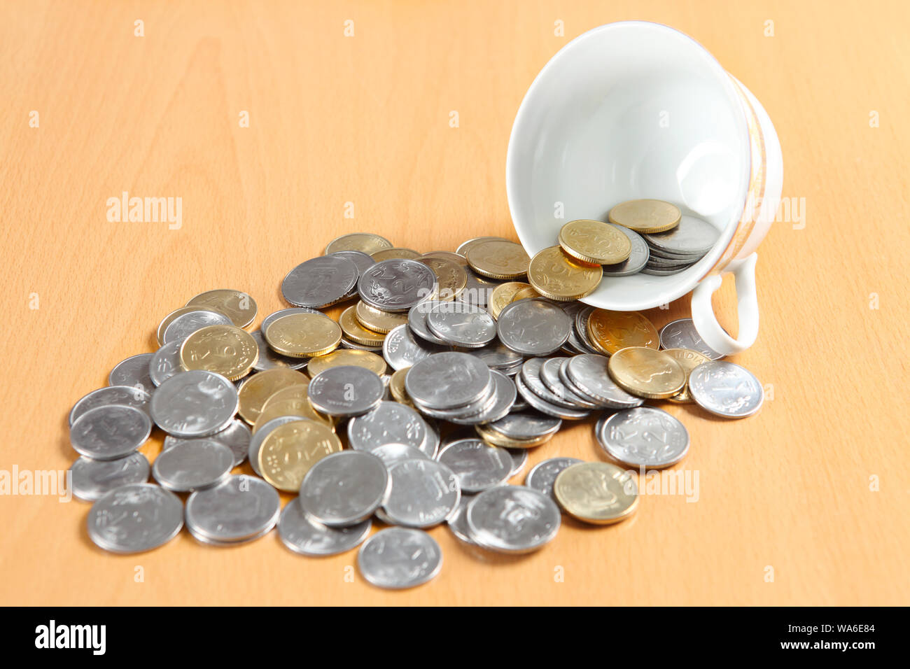 Coins spilling out of a tea cup Stock Photo - Alamy