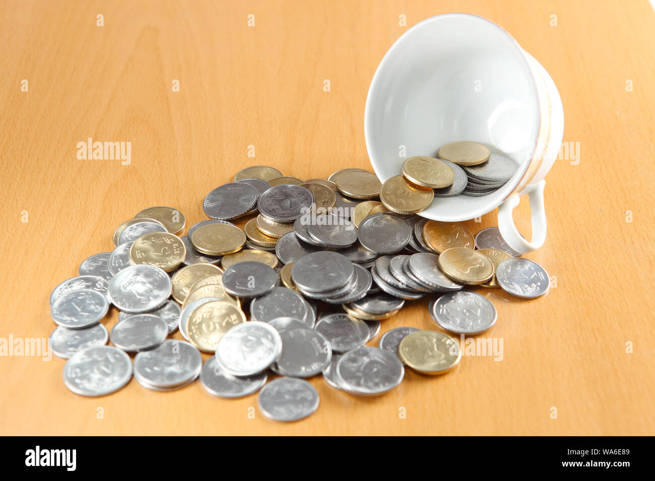 Coins spilling out of a tea cup Stock Photo - Alamy