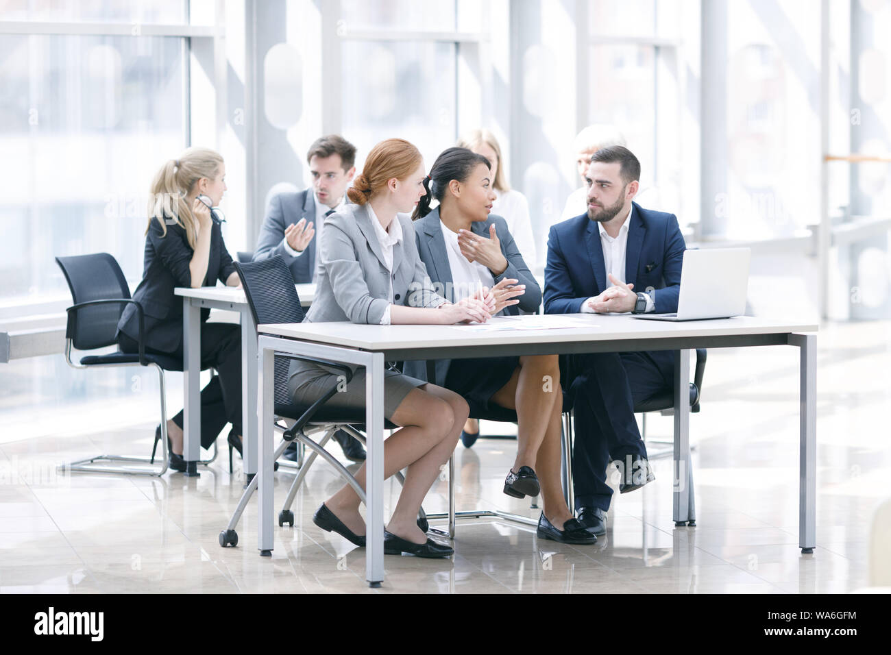 Business team sitting by the table with laptop and documents in office ...